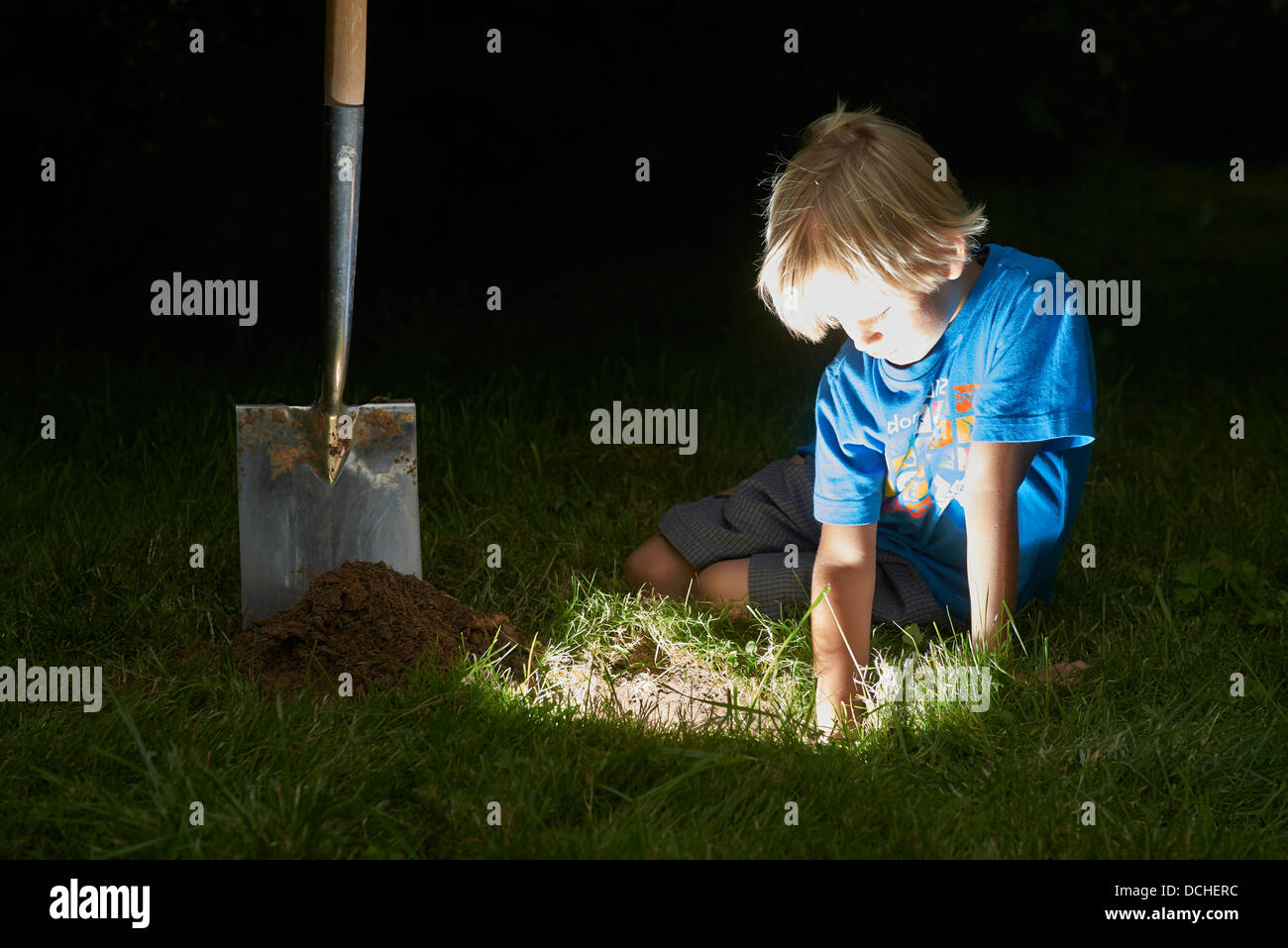 Child boy digging a treasure in magic hole in soil at dusk Stock Photo ...