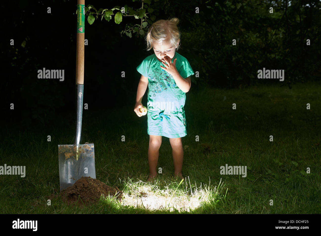 Child blond baby girl stands and digging for lighting hole in the ...