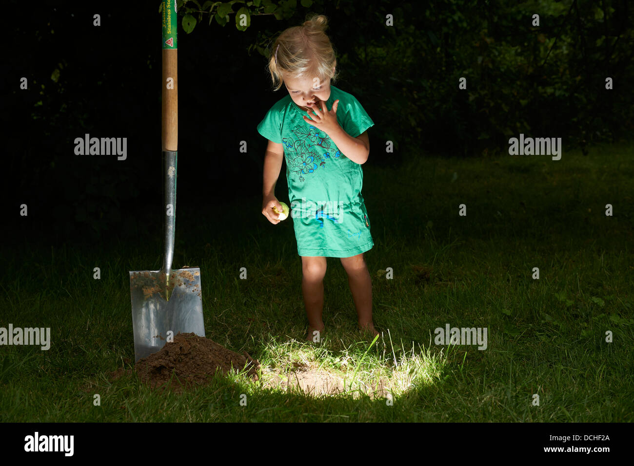 Child blond baby girl stands and digging for lighting hole in the ...
