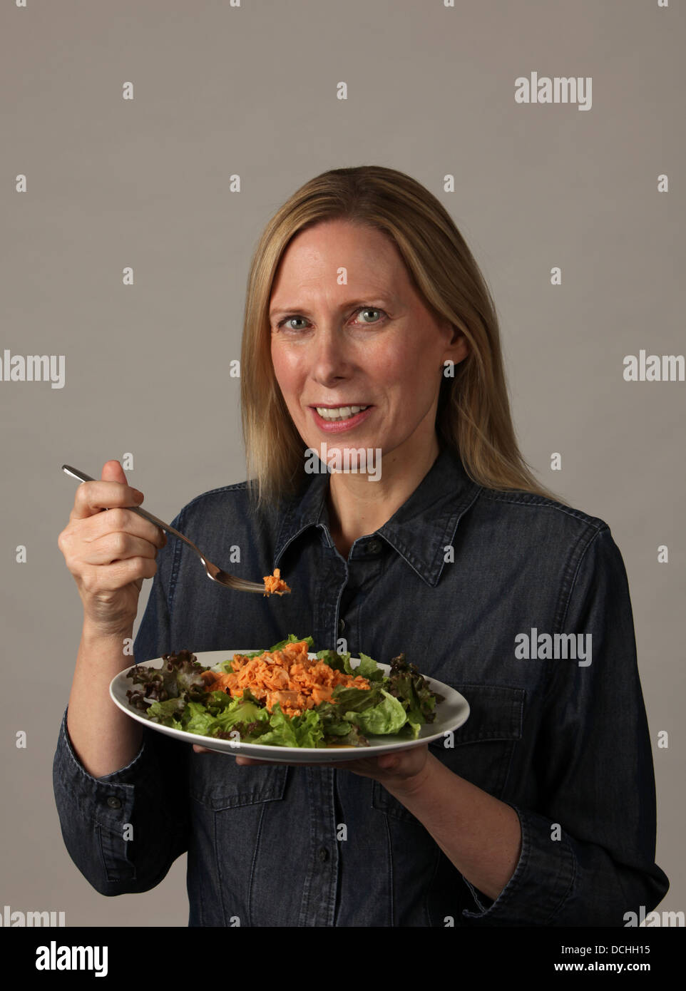 Health conscious and fit middle aged woman eating healthy green salad ...