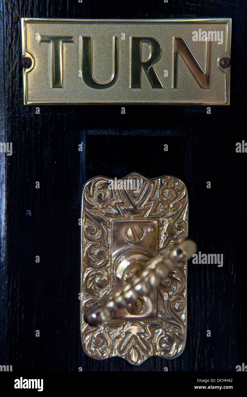 Detailed view of a brass turning door bell on a black door with sign ...