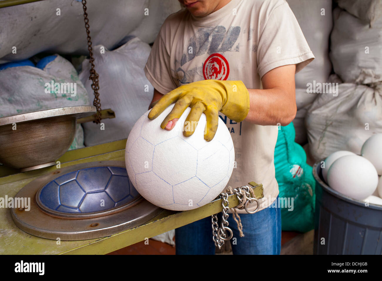 A man stamps a pattern onto the ball during the manufacturing process ...