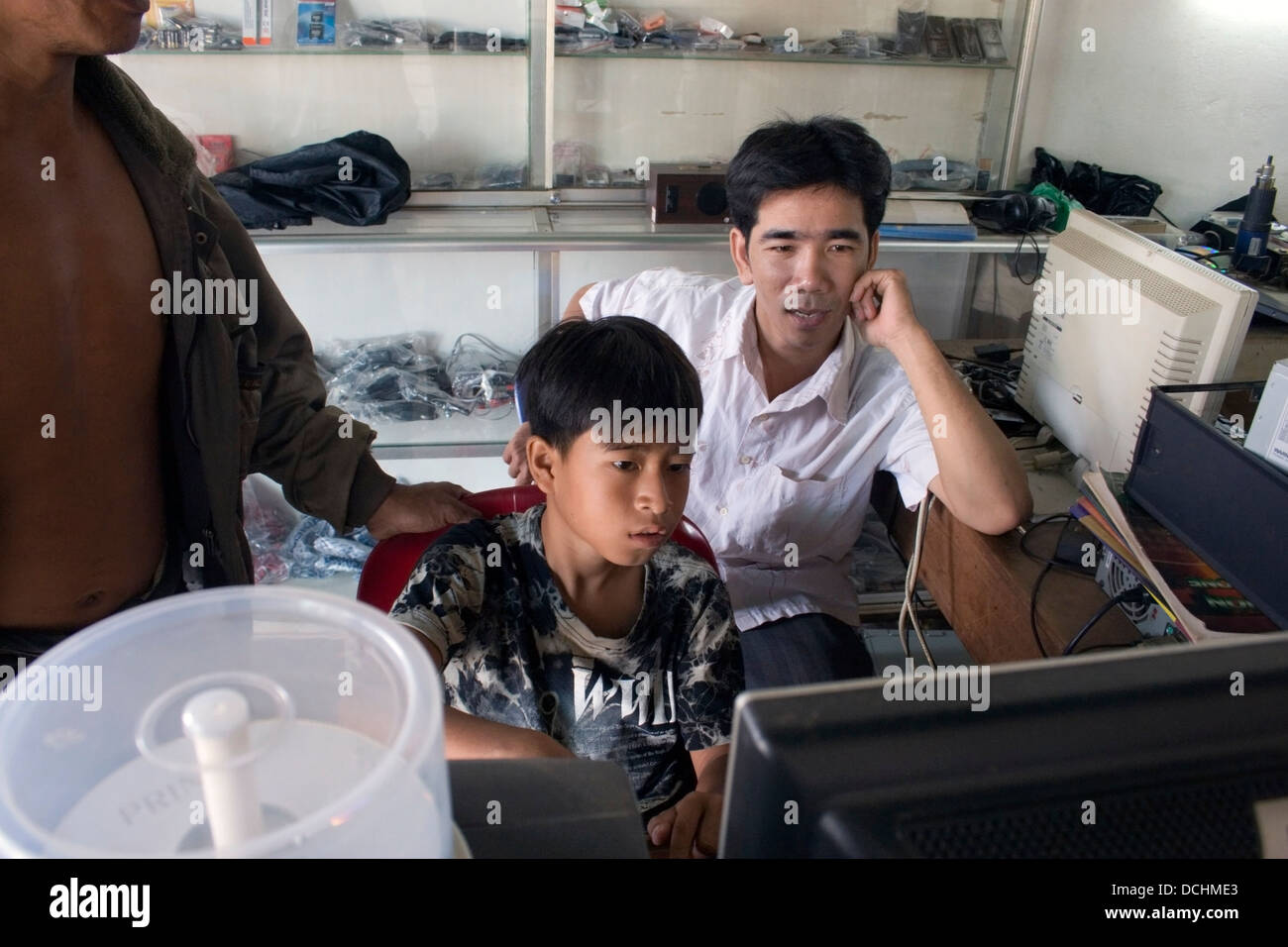 Two men and a boy are looking at a computer screen in Kampong Cham Cambodia Stock Photo - Alamy