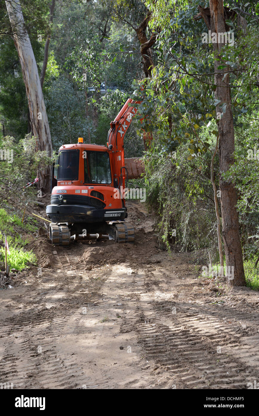 orange digger working on dirt drive in bush land Australia Stock Photo ...