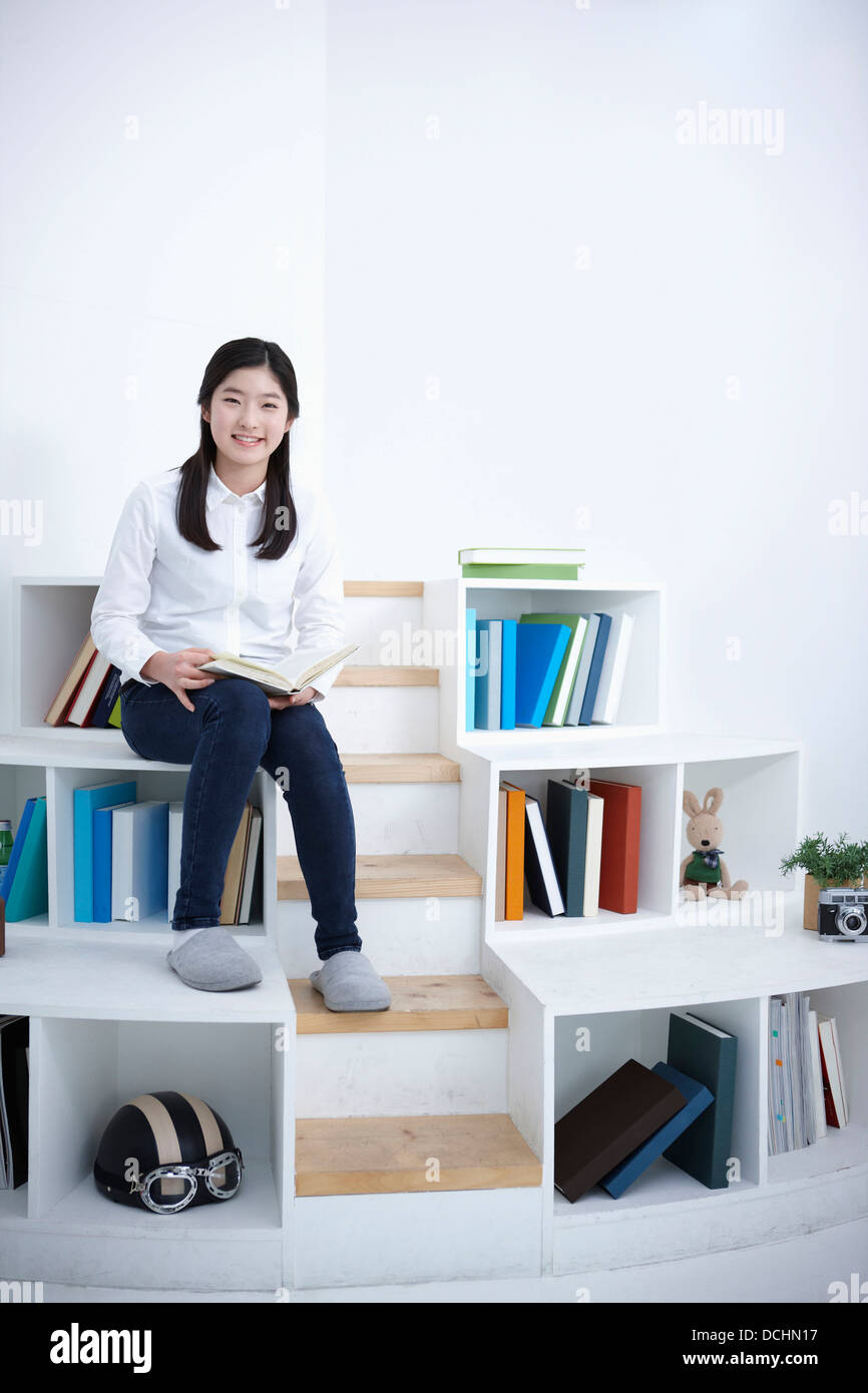 a student sitting on bookshelf Stock Photo - Alamy