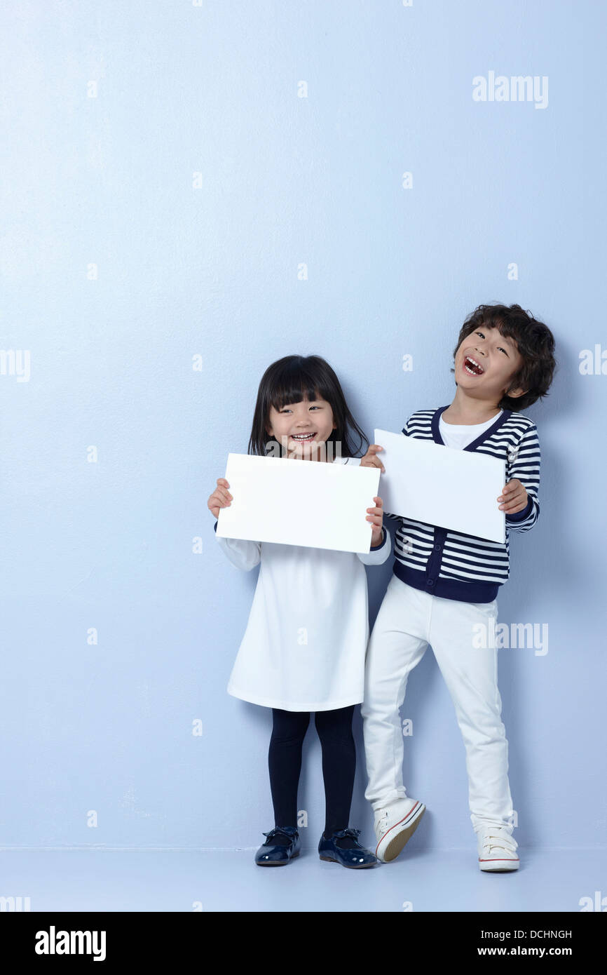 brother and sister holding blank papers Stock Photo - Alamy