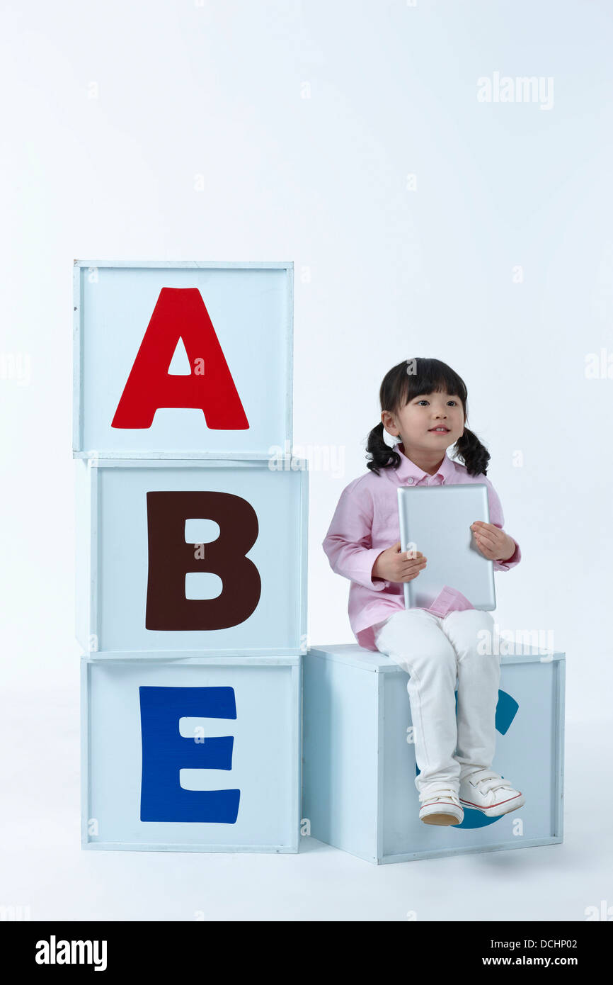 a girl sitting on boxes with alphabets Stock Photo - Alamy