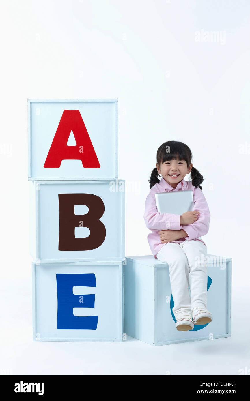 a girl sitting on boxes with alphabets Stock Photo - Alamy