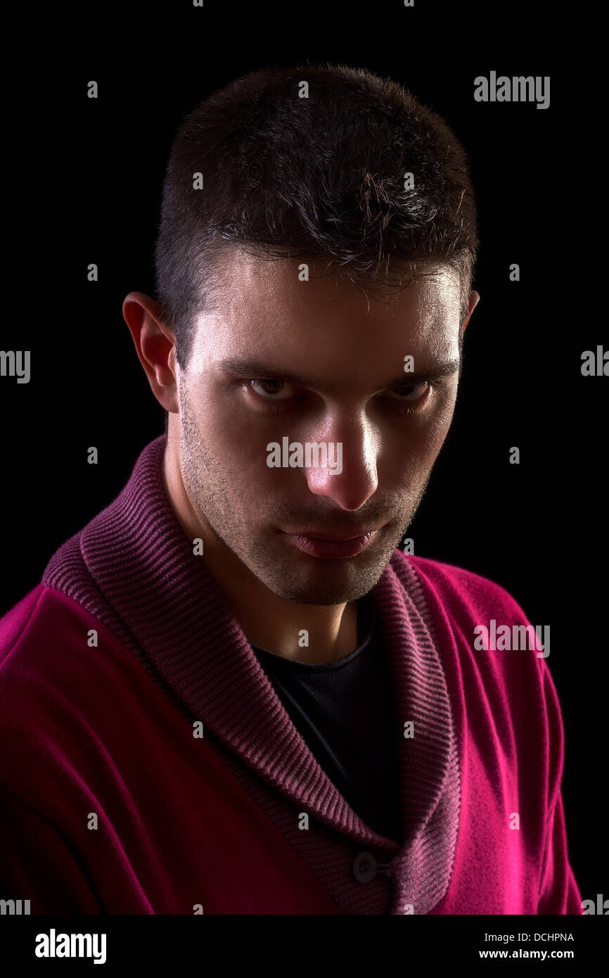 Face view of a young urban man with a mean look isolated on a black ...