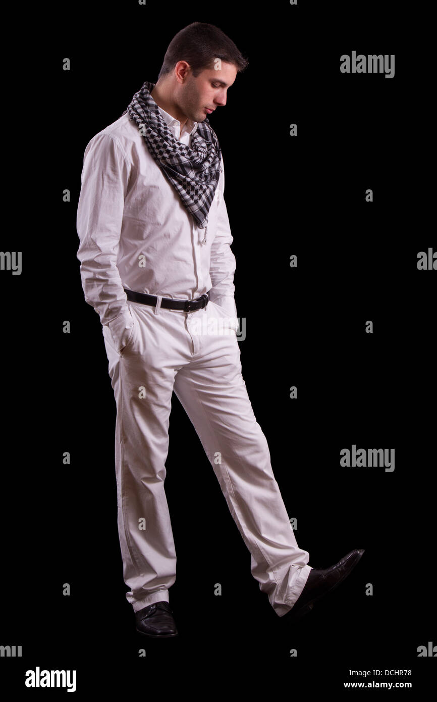 View of a young urban styled fashioned man standing isolated on a black ...