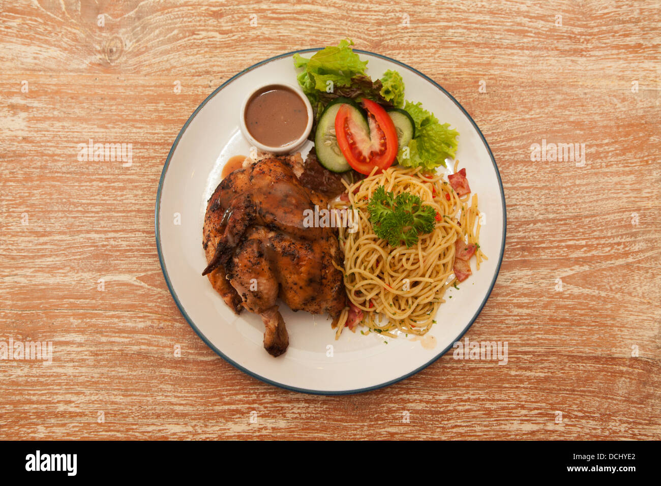Grilled chicken leg served on round white plate with bread tomatoe ...