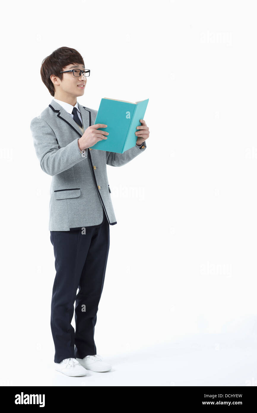 a boy in a school uniform reading a book Stock Photo - Alamy