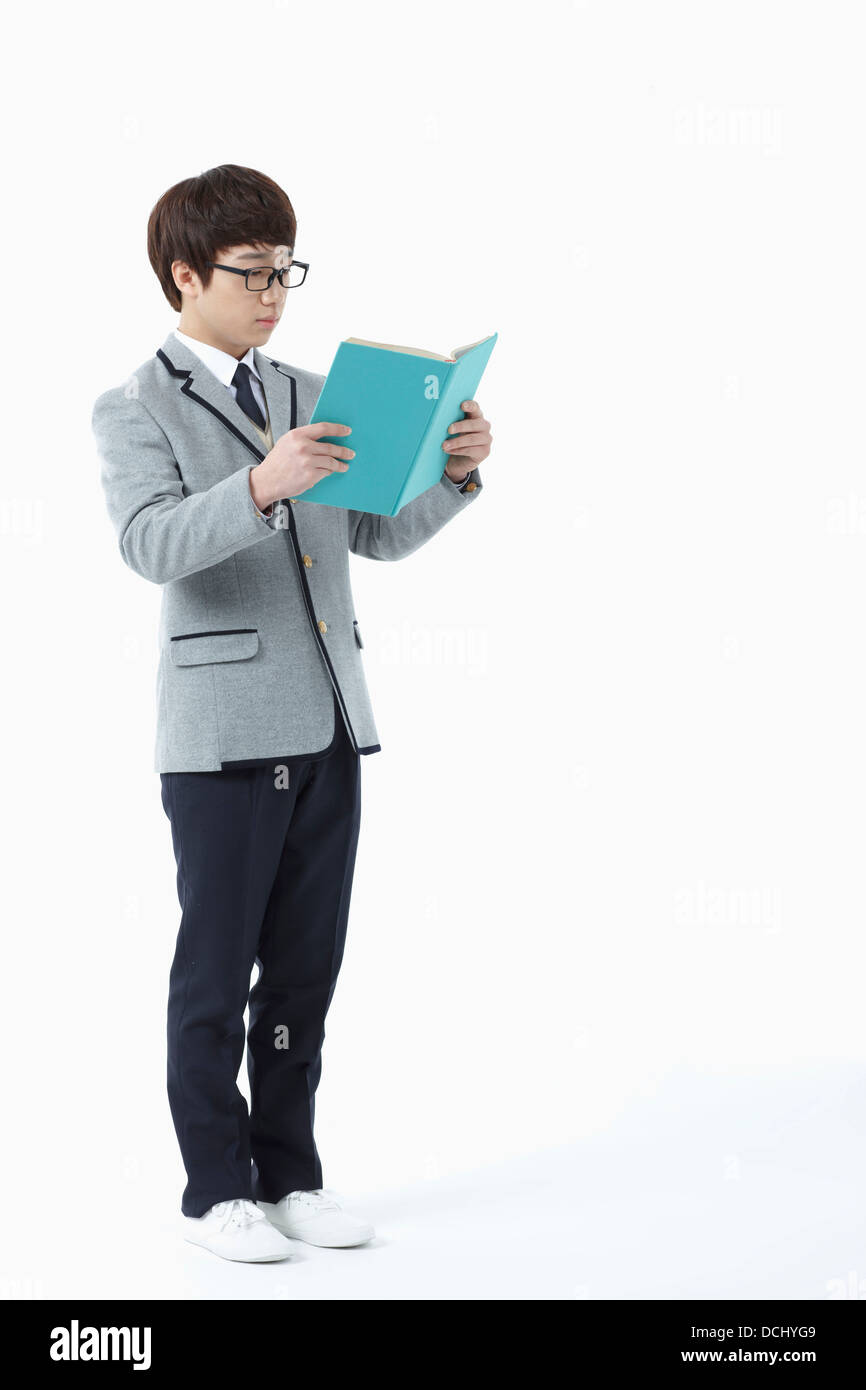 a boy in a school uniform reading a book Stock Photo - Alamy