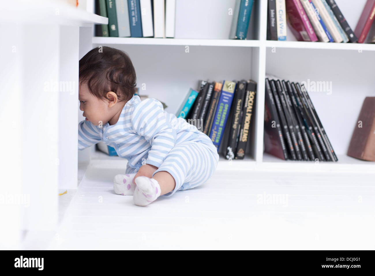 a baby playing while sitting under a desk Stock Photo - Alamy