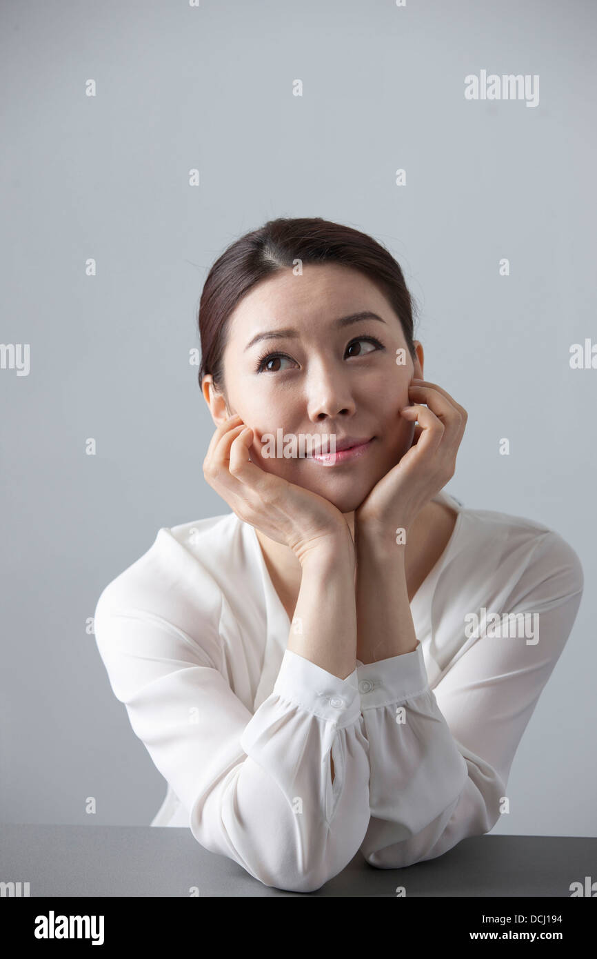 a woman thinking while sitting at a desk Stock Photo - Alamy