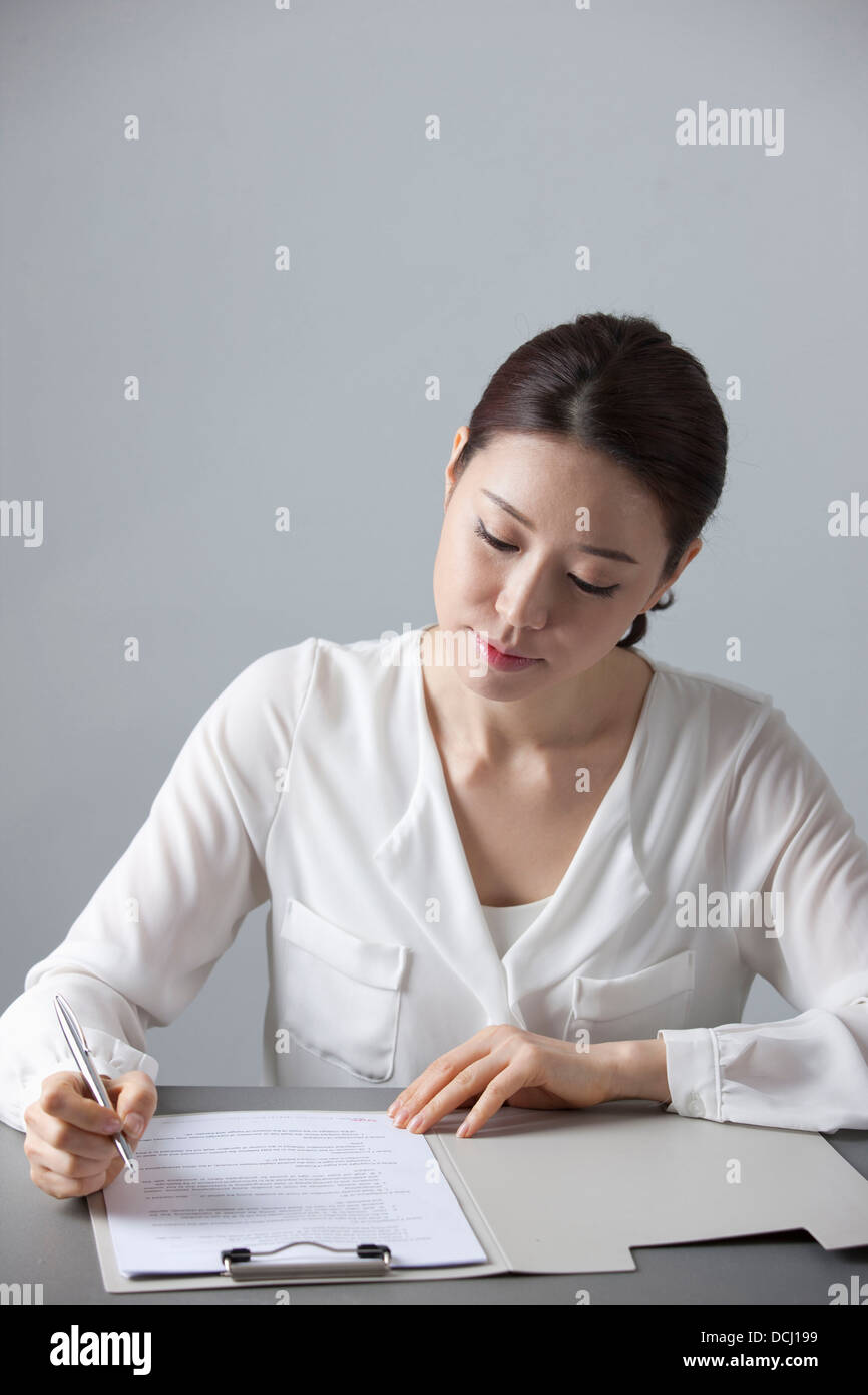 a woman writing something on a folder Stock Photo - Alamy