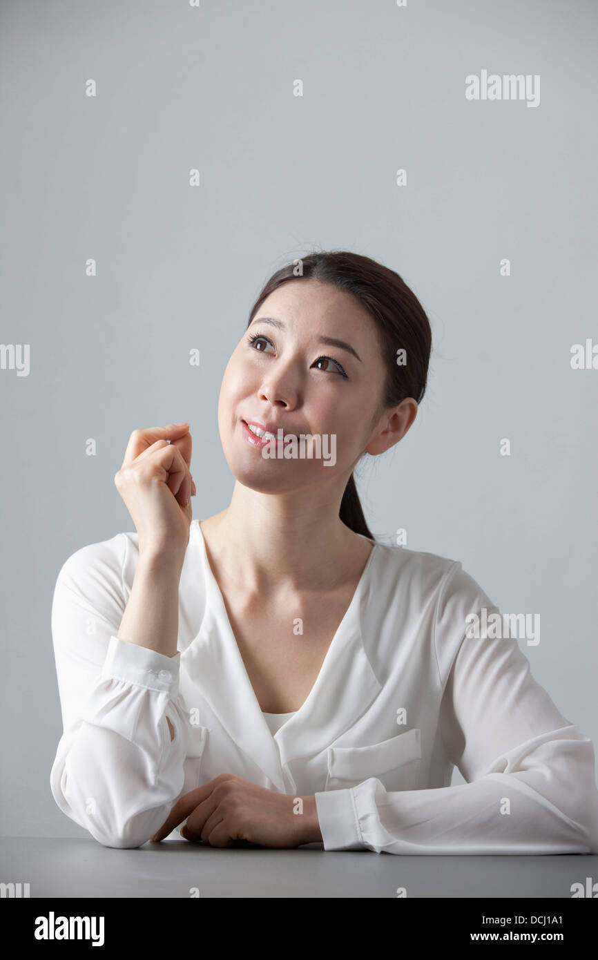 a woman thinking while sitting at a desk Stock Photo - Alamy