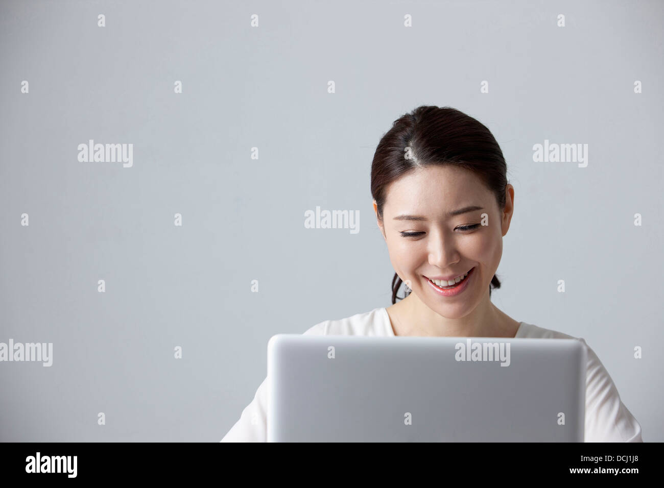 a woman smiling while using a laptop Stock Photo - Alamy