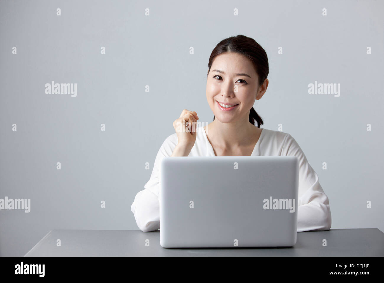 a woman smiling while using a laptop Stock Photo - Alamy