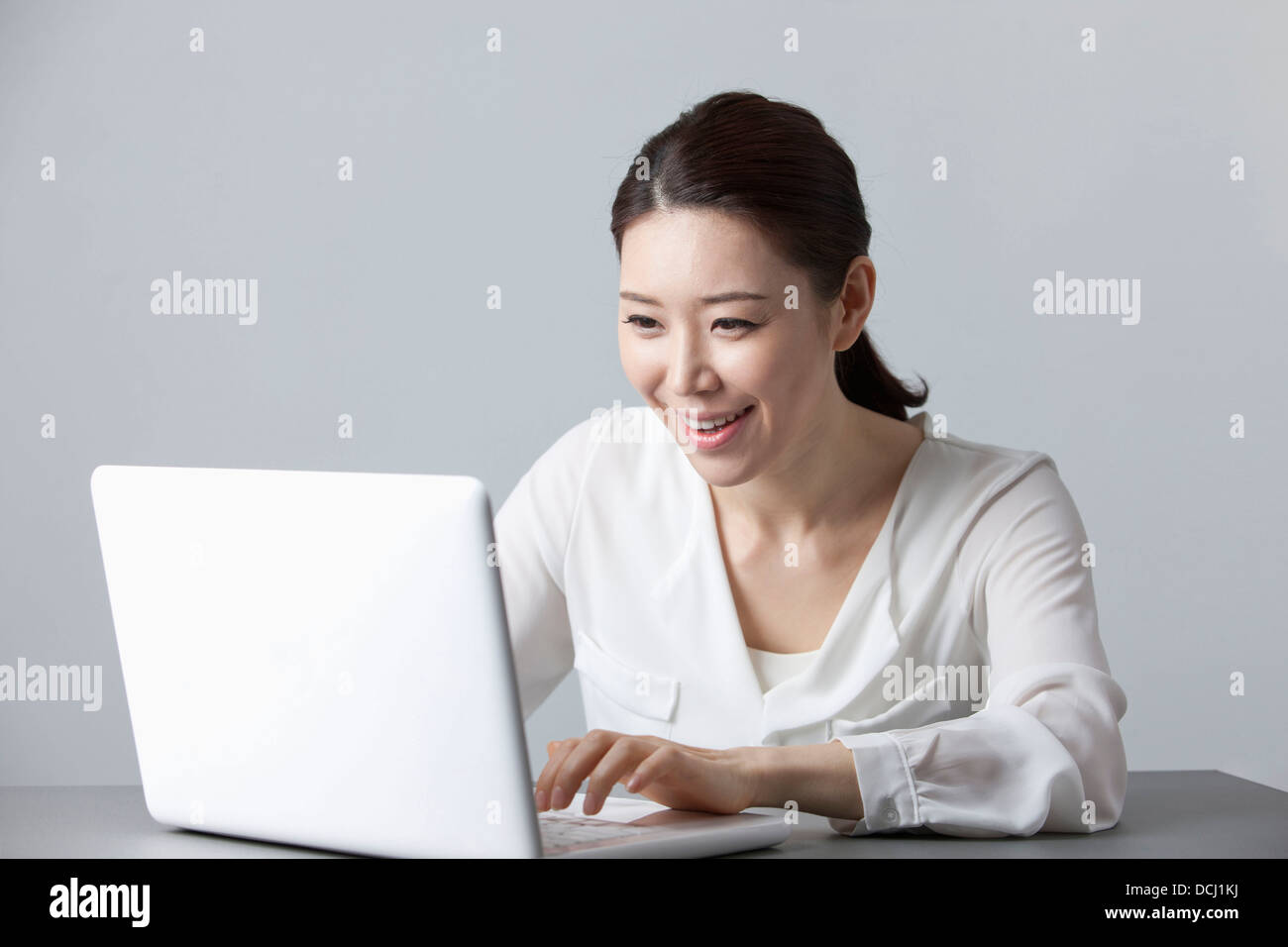 a woman smiling while using a laptop Stock Photo - Alamy