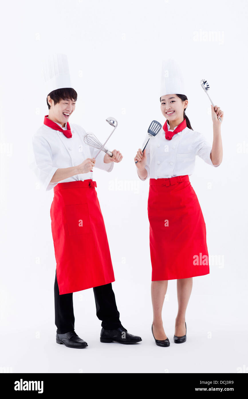 female and male cook in red apron posing with kitchen utensils Stock ...