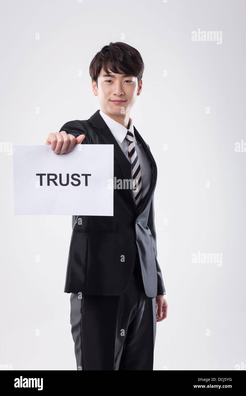 a business man with a paper saying trust Stock Photo - Alamy