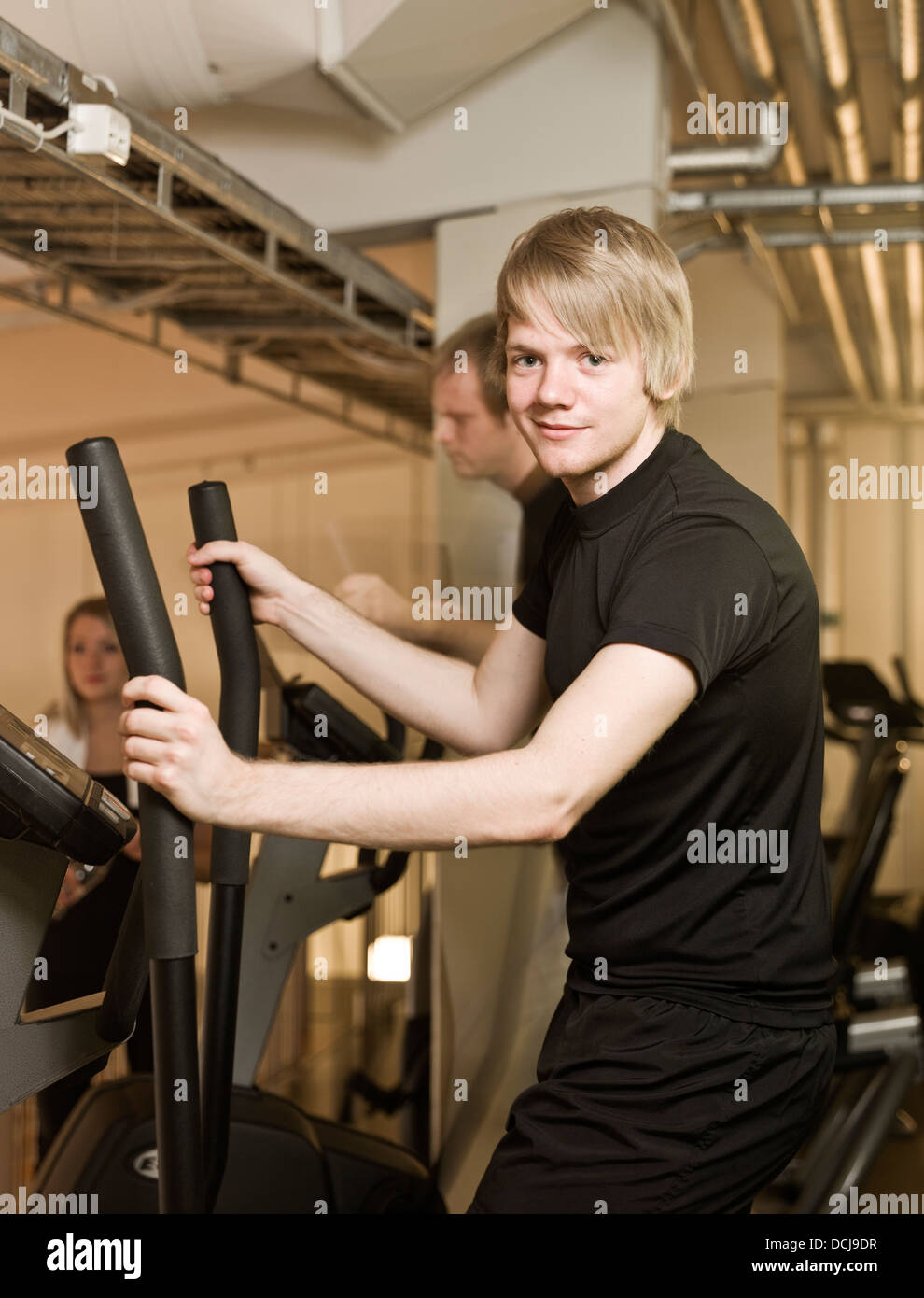 Young man using an exercise machine Stock Photo - Alamy