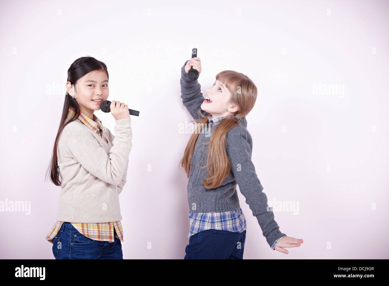 two girls singing a song with microphones Stock Photo - Alamy