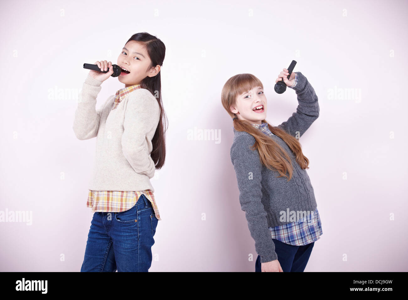 two girls singing a song with microphones Stock Photo - Alamy