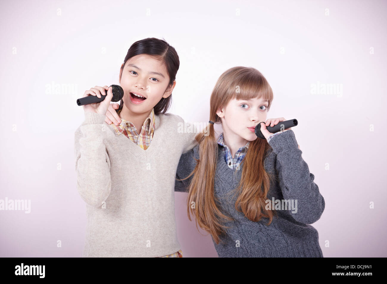 two girls singing a song with microphones Stock Photo - Alamy