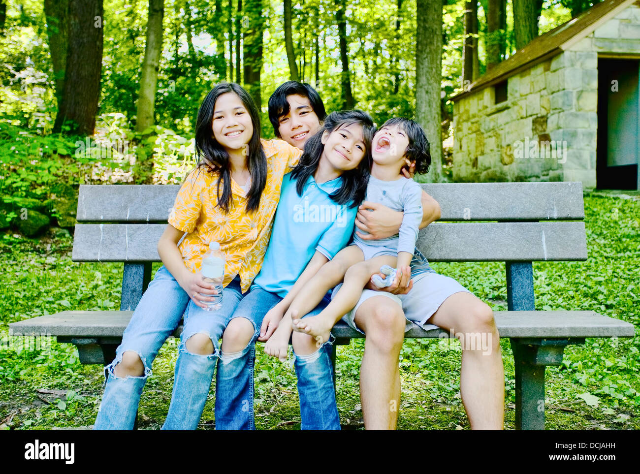 Four kids sitting on bench Stock Photo - Alamy