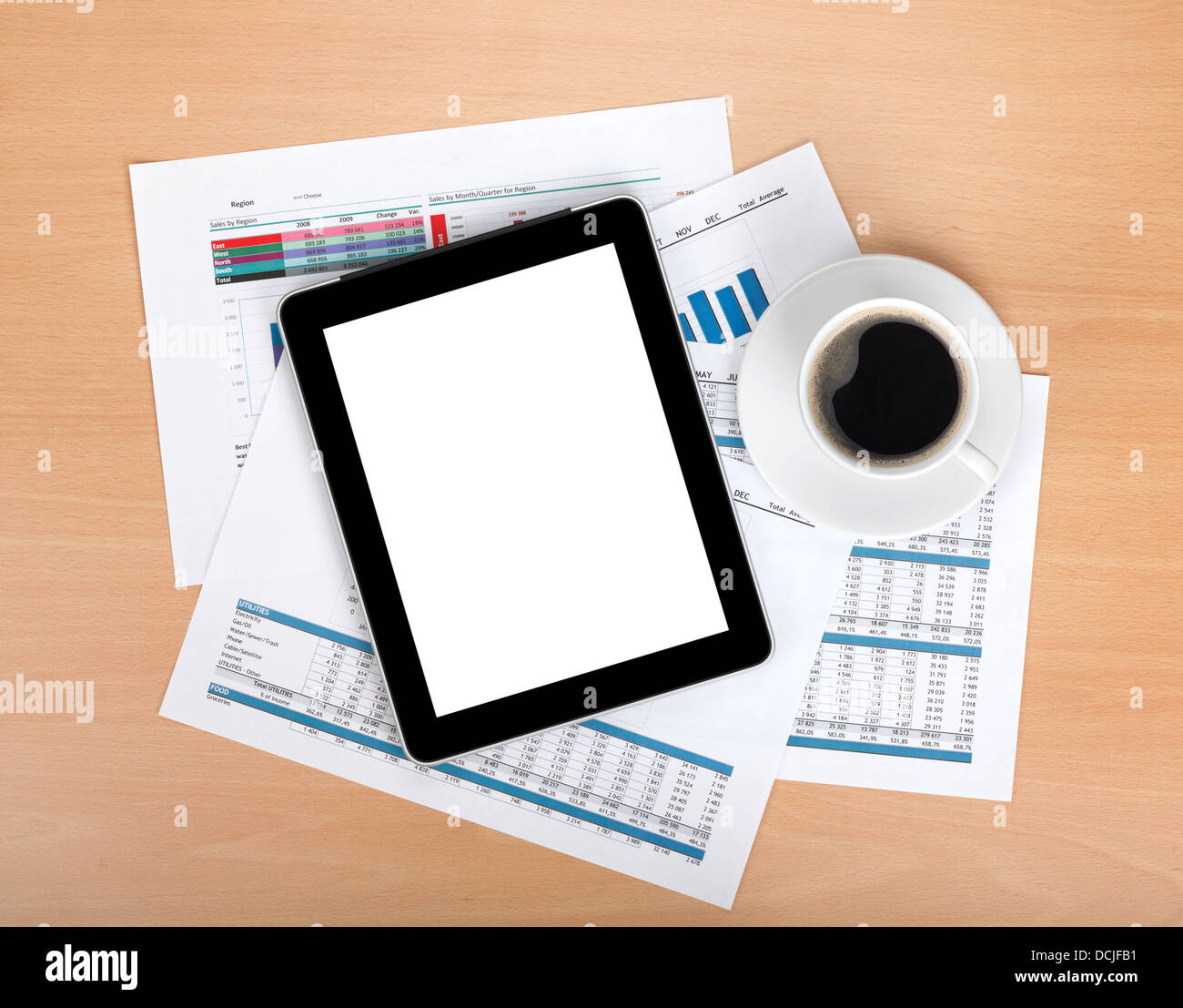 Tablet and notepad over papers with numbers and charts and coffee cup ...