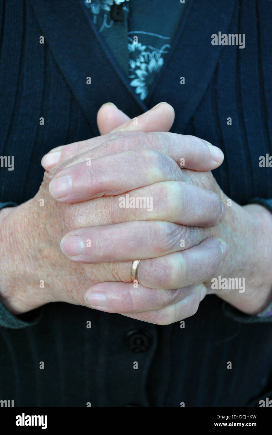 praying hands of an older person with a dark blue sweater Stock Photo ...