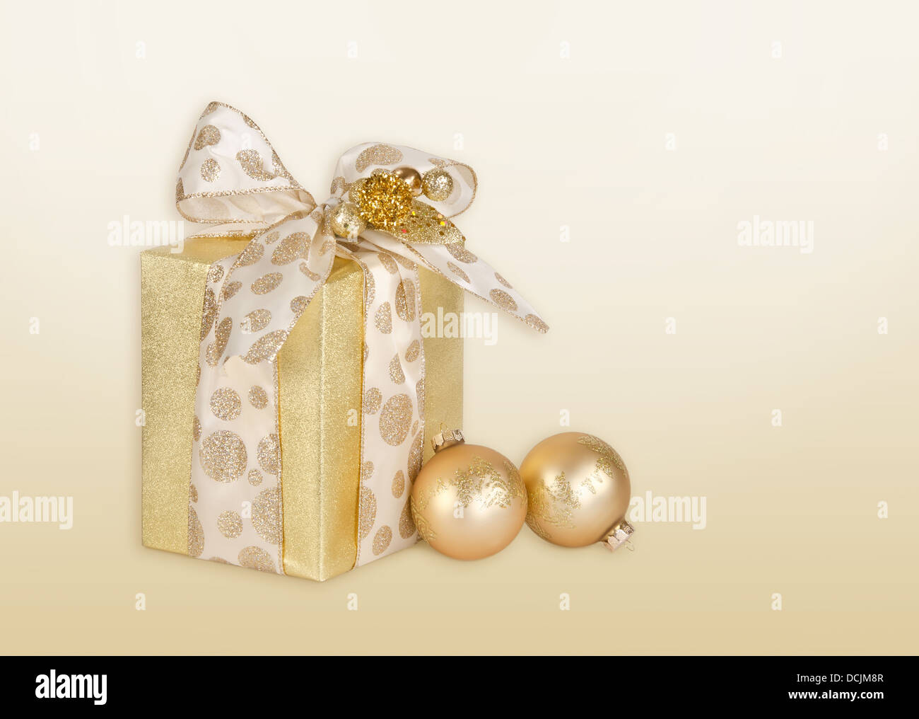 Golden gift wrapped present with dotted bow and golden Christmas ball ...
