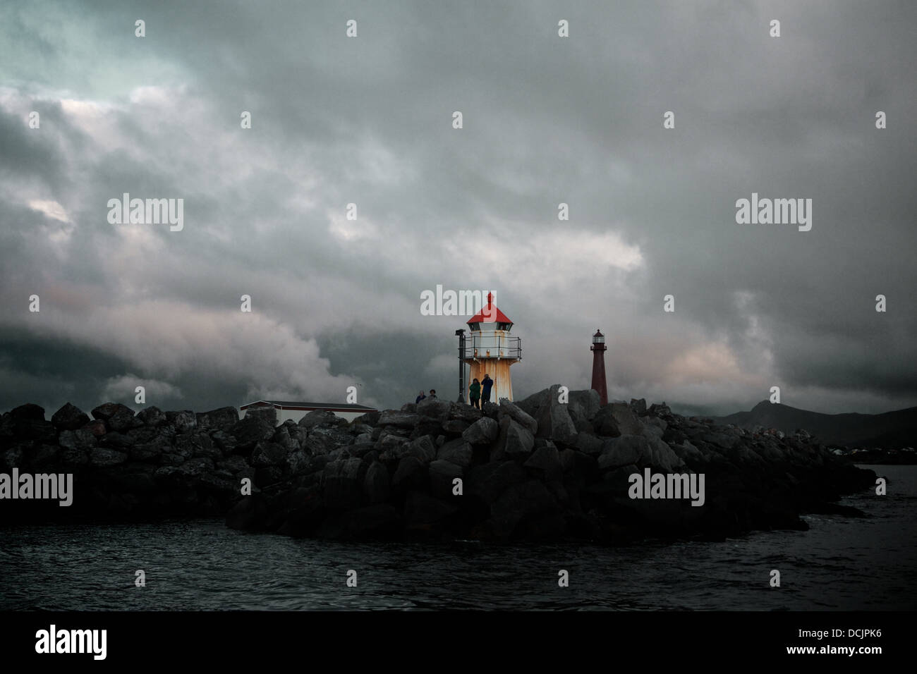Vivid red and rust lighthouse on foreboding outcrop Stock Photo - Alamy