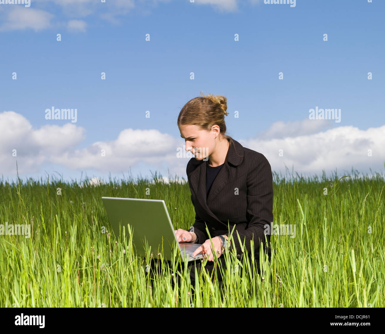 Woman sitting outdoor in thye grass with her laptop Stock Photo - Alamy