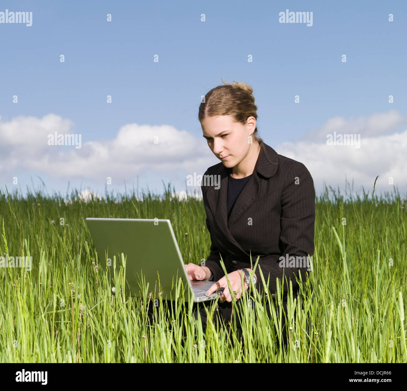 Woman sitting outdoor in the grass with her laptop Stock Photo - Alamy