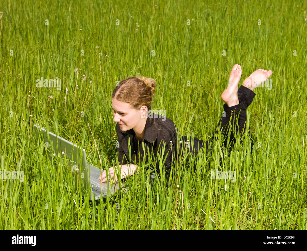 Woman with her computer in the grass Stock Photo - Alamy