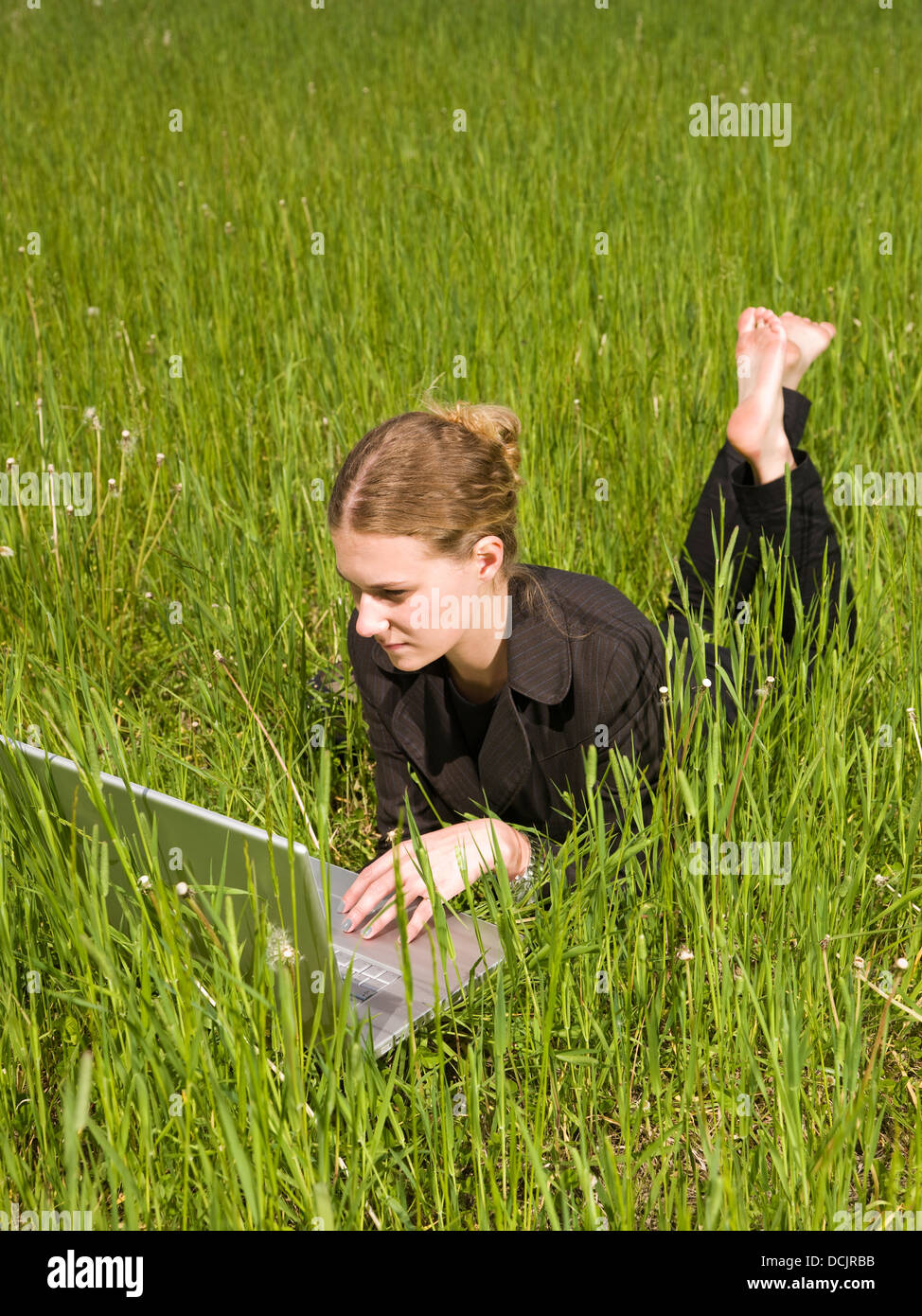 Woman with her computer in the grass Stock Photo - Alamy