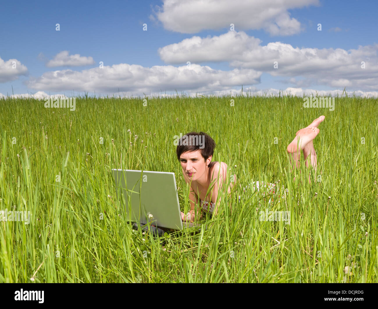 Woman with her computer in the grass Stock Photo - Alamy