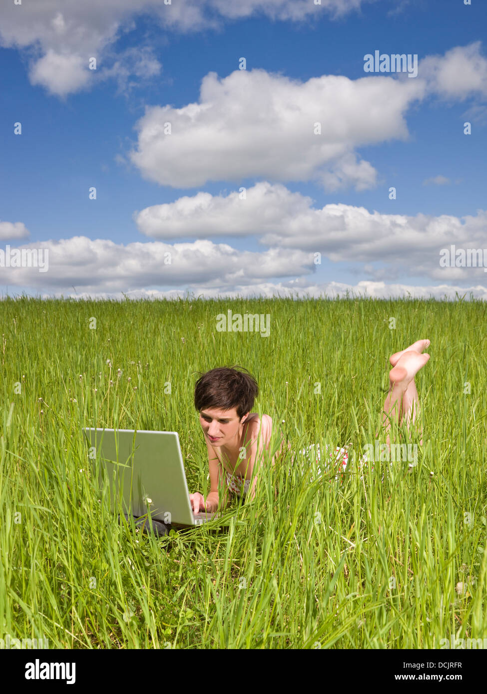 Woman with her computer in the grass Stock Photo - Alamy
