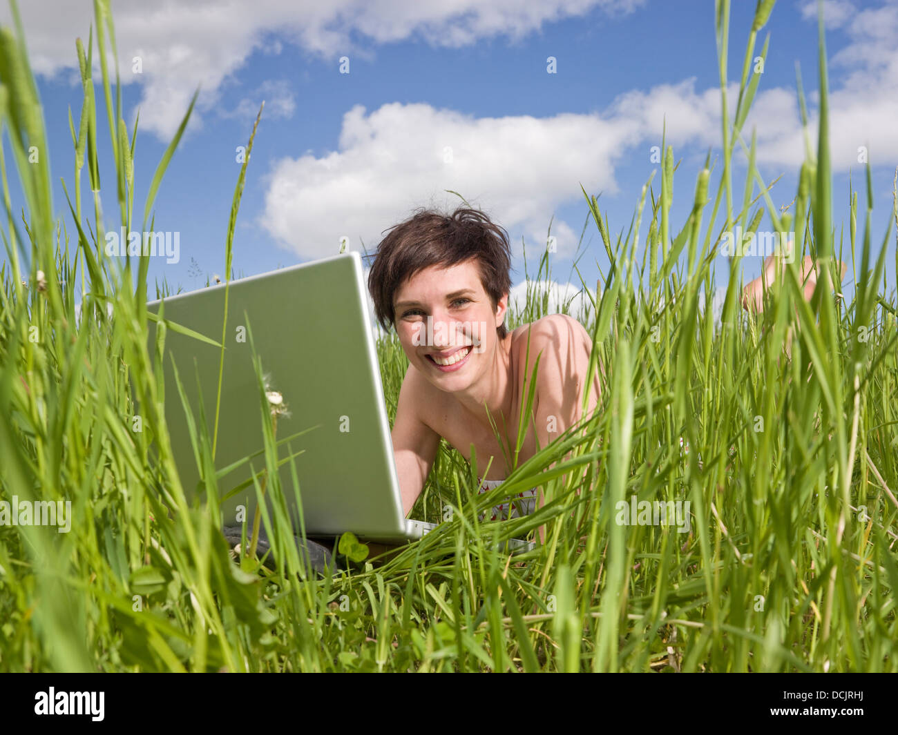 Woman with her computer in the grass Stock Photo - Alamy