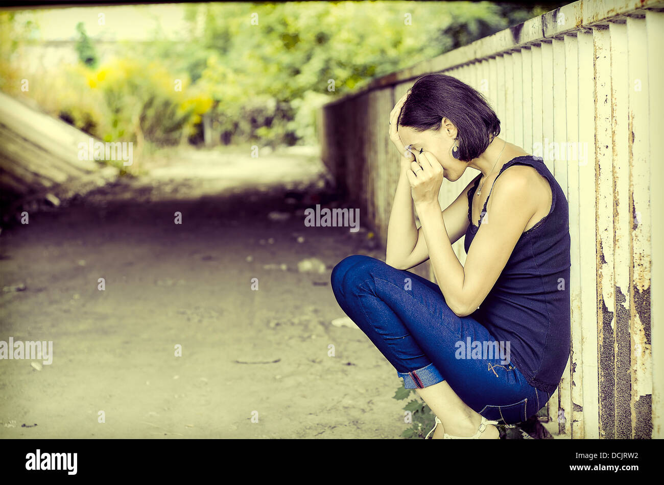 Weeping, sad woman sitting alone under a bridge Stock Photo - Alamy