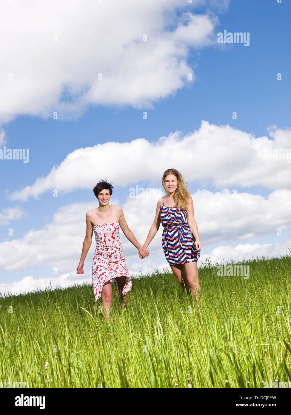Two women holding hands on a field Stock Photo - Alamy