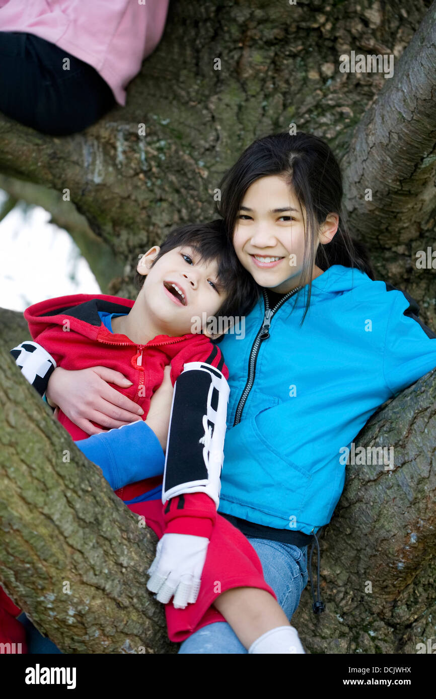 Sister holding disabled brother in tree Stock Photo - Alamy