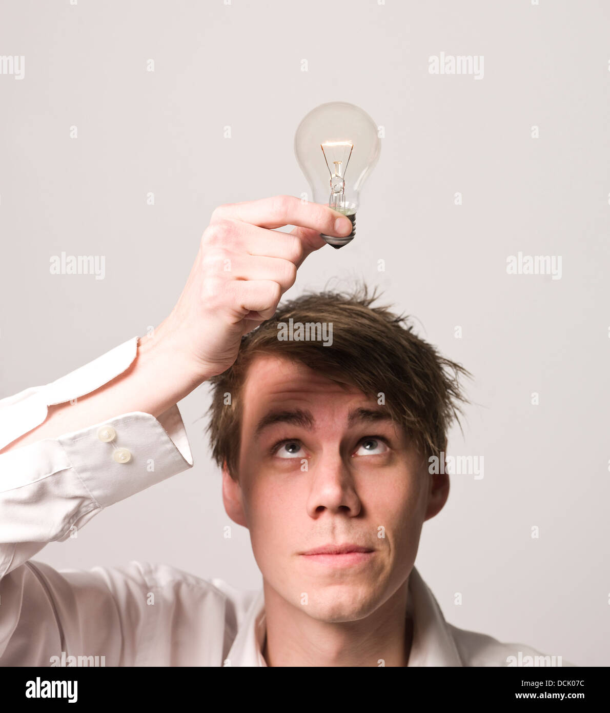 Man holding electric light bulb over his head Stock Photo - Alamy