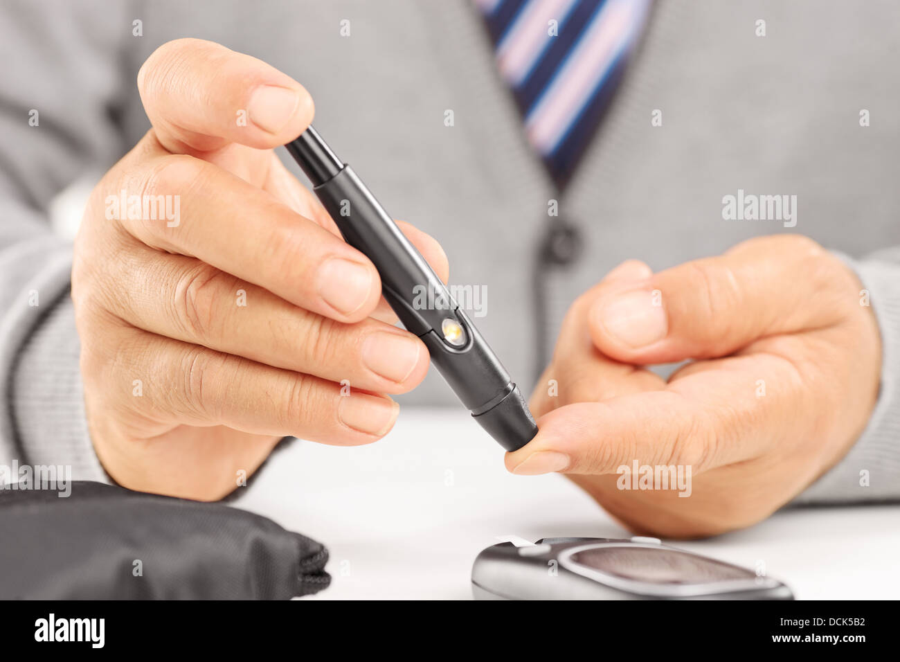 Mature diabetic patient measuring sugar level in blood using glucometer ...