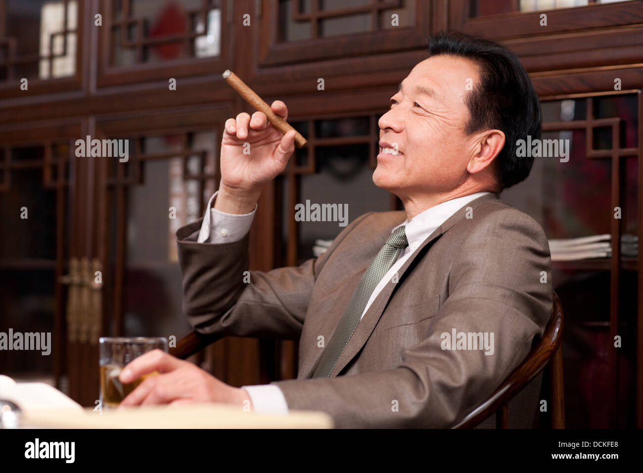 Successful businessman enjoying cigar Stock Photo - Alamy