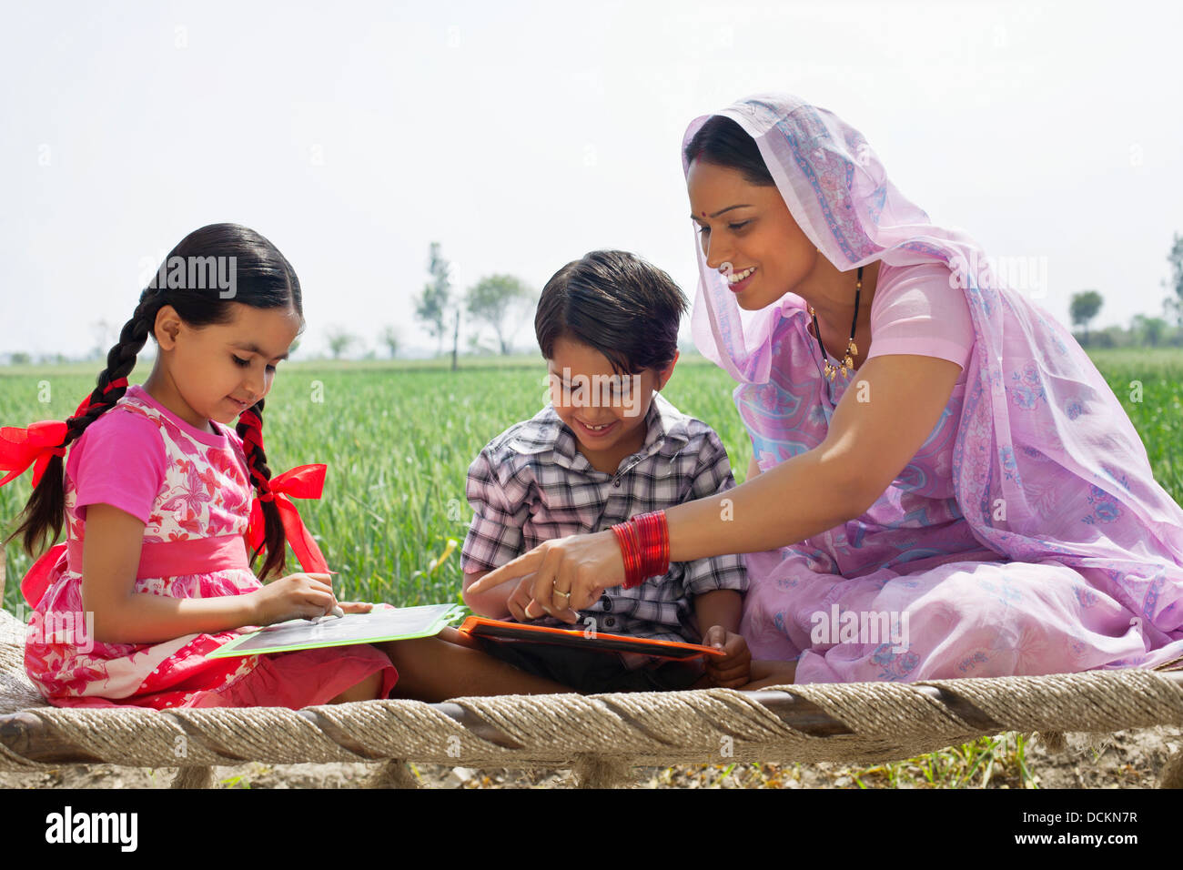 Happy mother guiding children with their homework Stock Photo - Alamy
