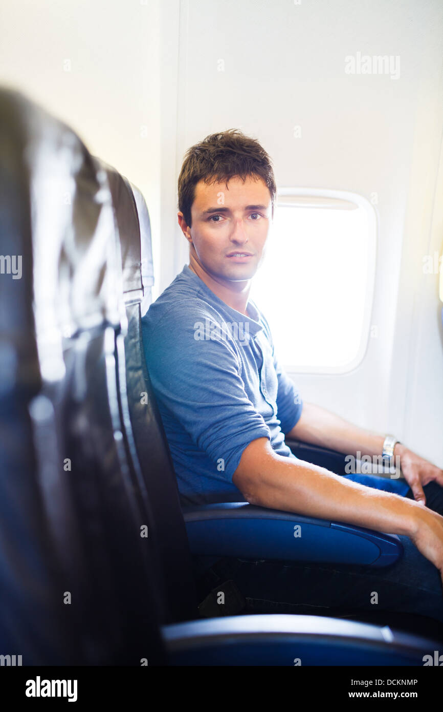 Handsome young man on board of an airplane during flight Stock Photo ...